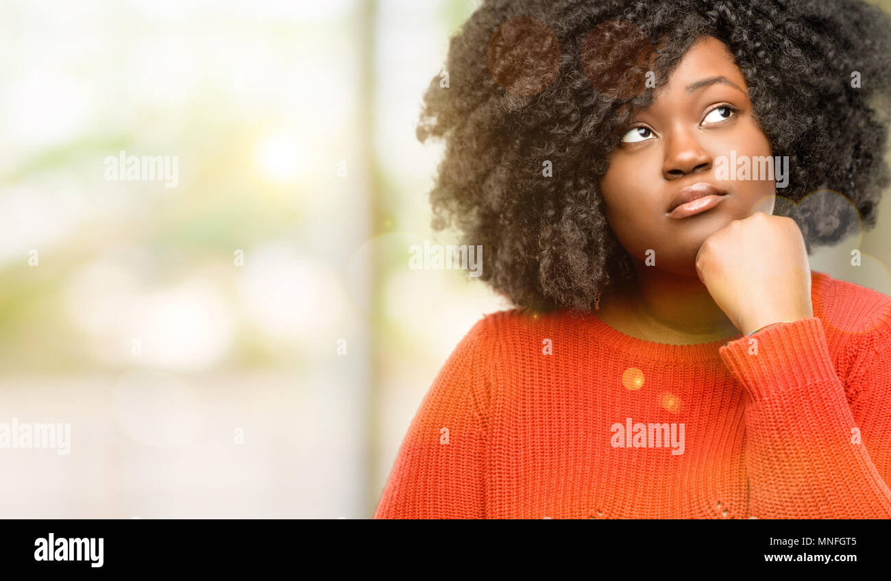 Beautiful african woman thinking and looking up expressing doubt and ...