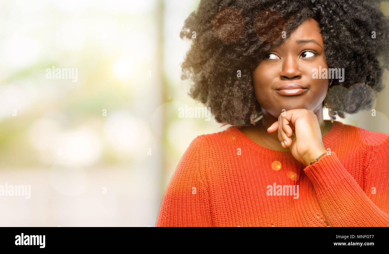 Beautiful african woman thinking and looking up expressing doubt and ...