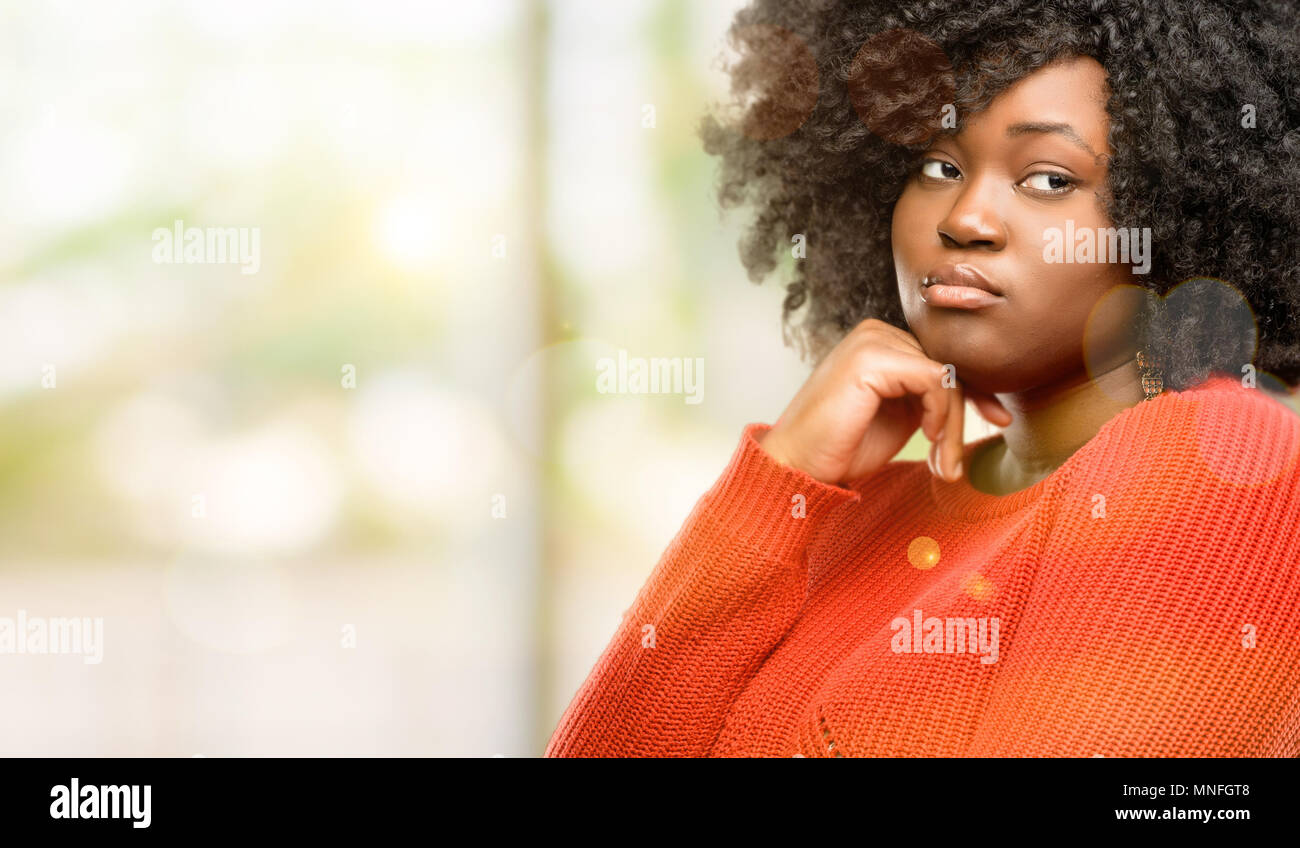 Beautiful african woman thinking and looking up expressing doubt and ...