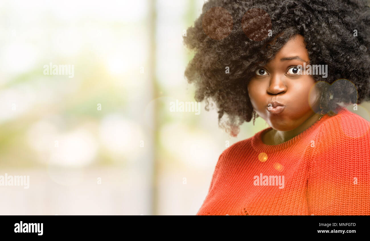 Beautiful african woman puffing out cheeks, having fun making funny ...