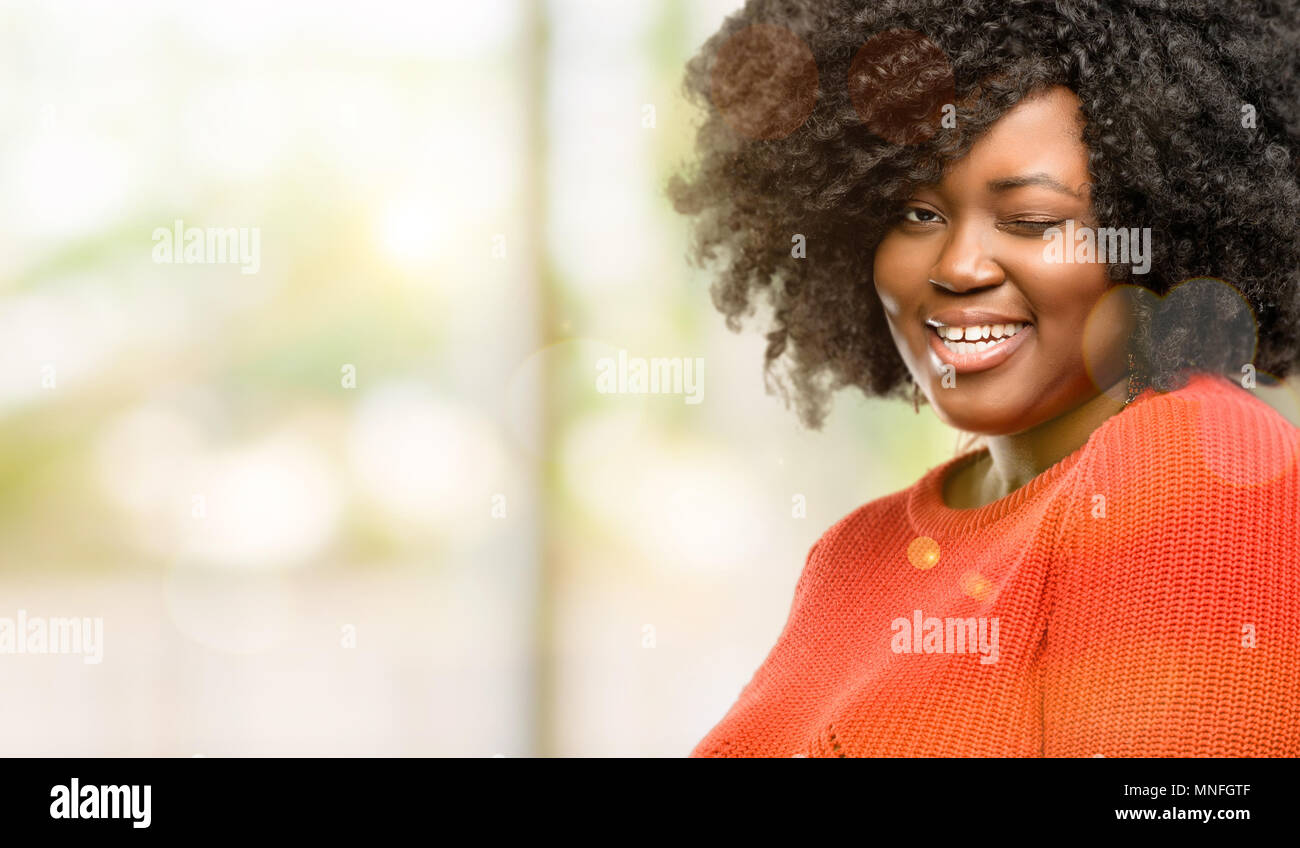 Beautiful african woman blinking eyes with happy gesture, outdoor Stock ...