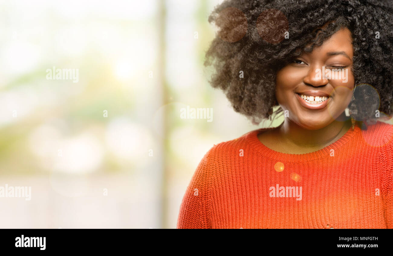 Beautiful african woman blinking eyes with happy gesture, outdoor Stock ...