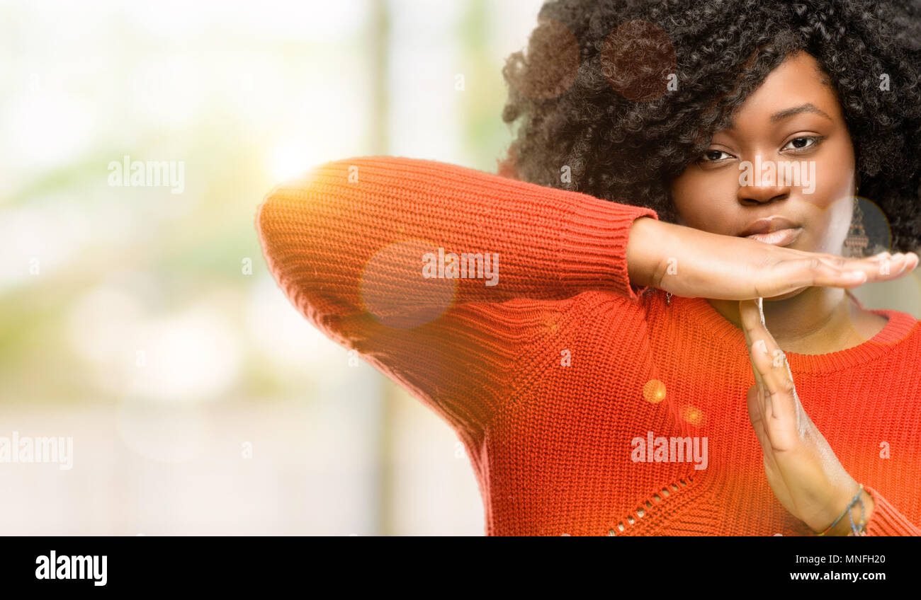 Beautiful african woman serious making a time out gesture with hands ...