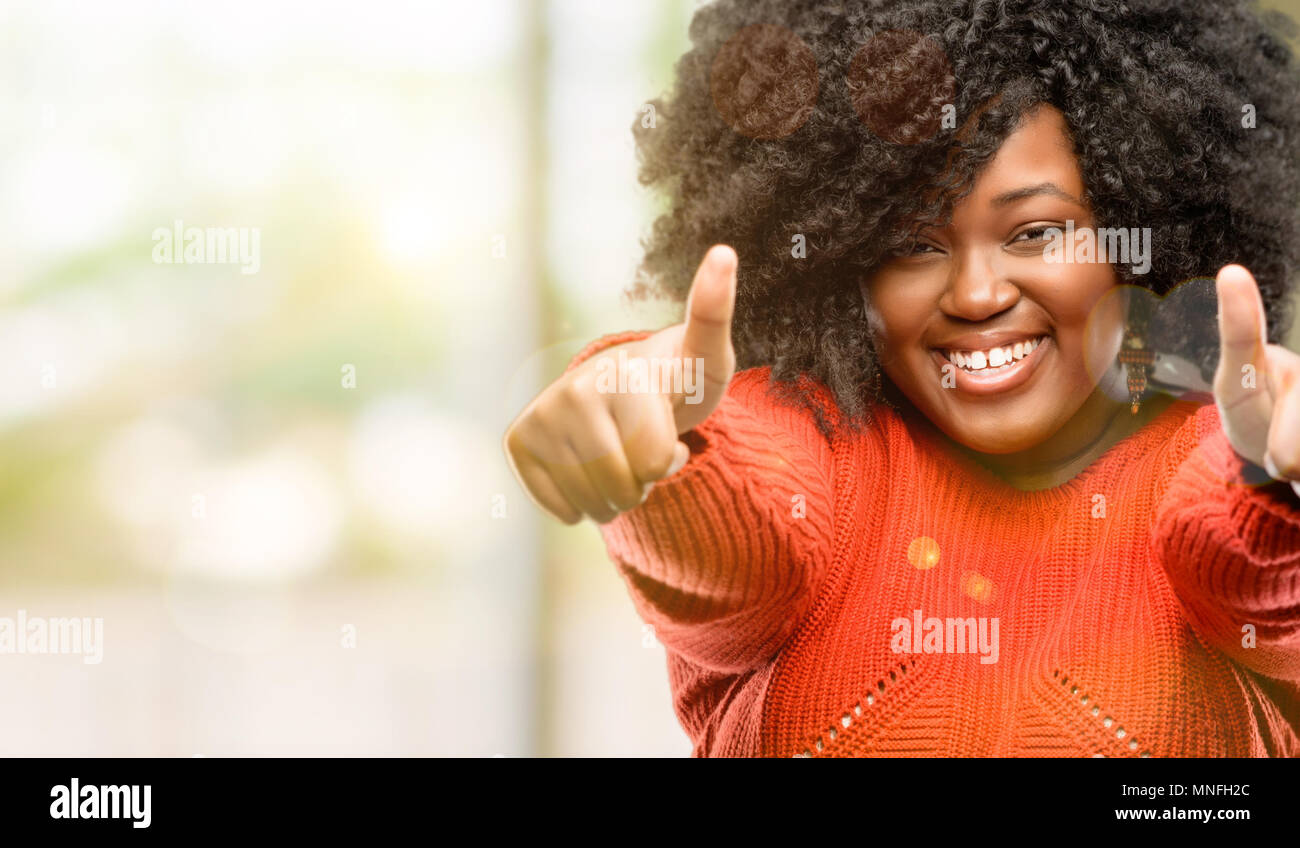 Beautiful african woman stand happy and positive with thumbs up ...