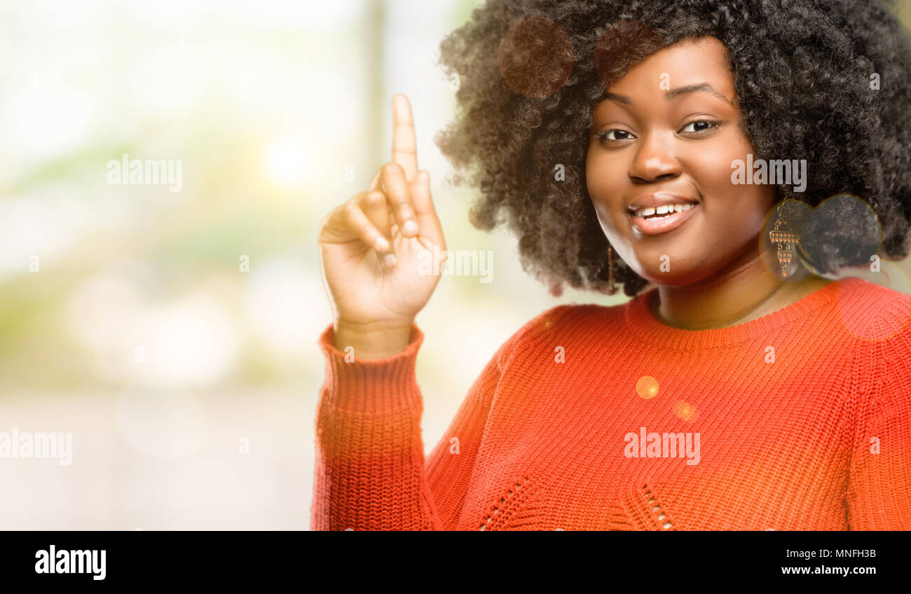 Beautiful african woman happy and surprised cheering pointing up ...