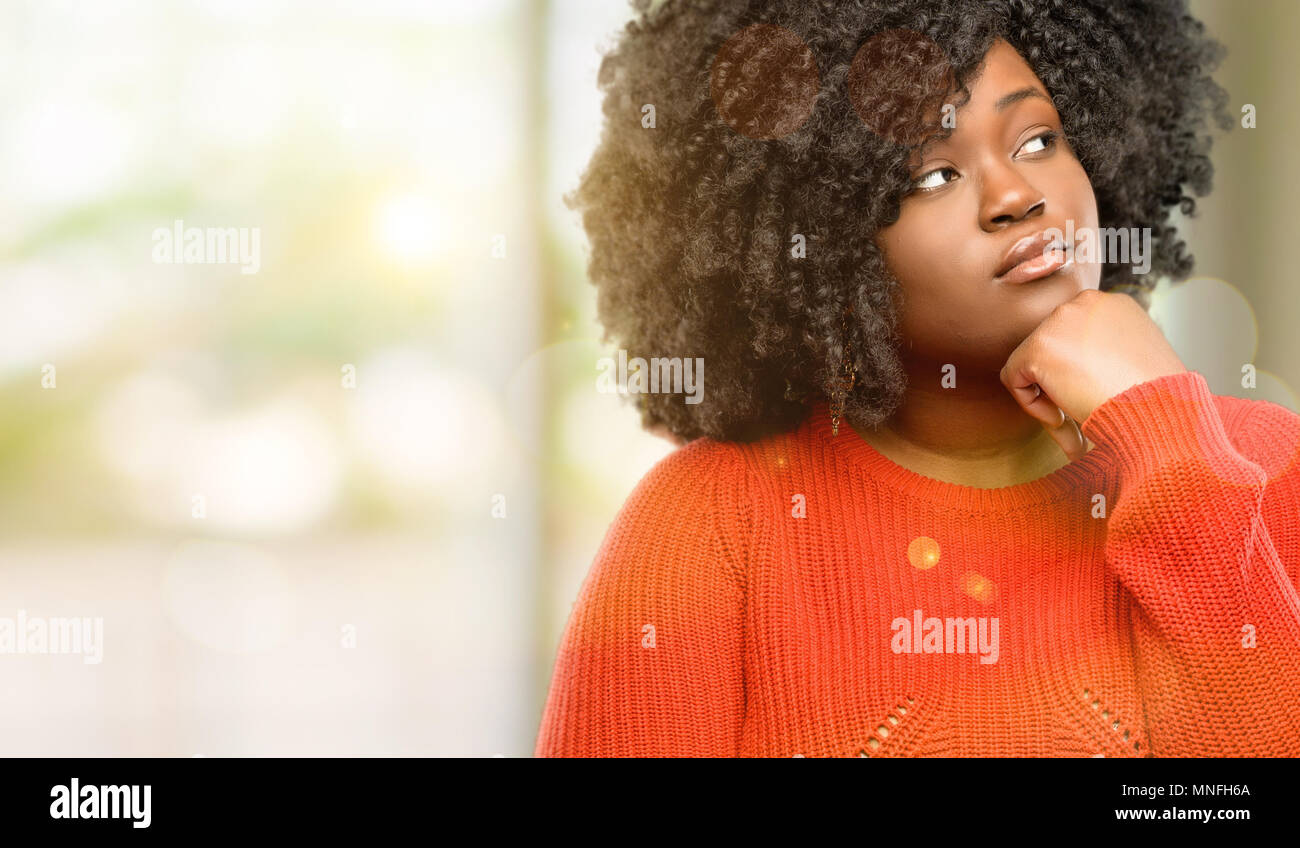 Beautiful african woman thinking and looking up expressing doubt and ...