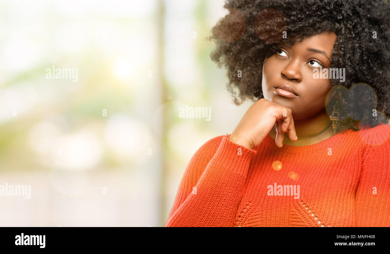 Beautiful african woman thinking and looking up expressing doubt and ...