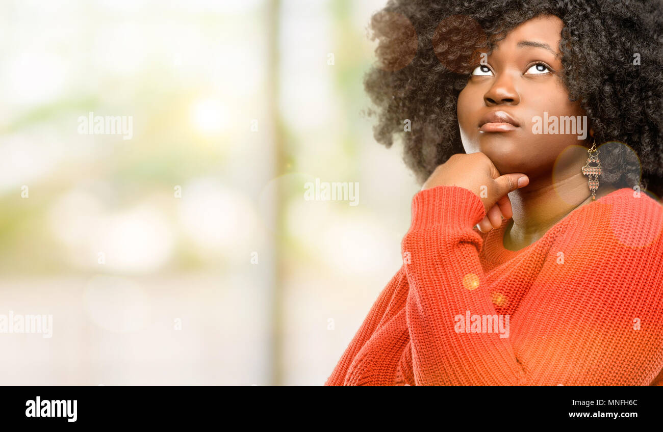 Beautiful african woman thinking and looking up expressing doubt and ...