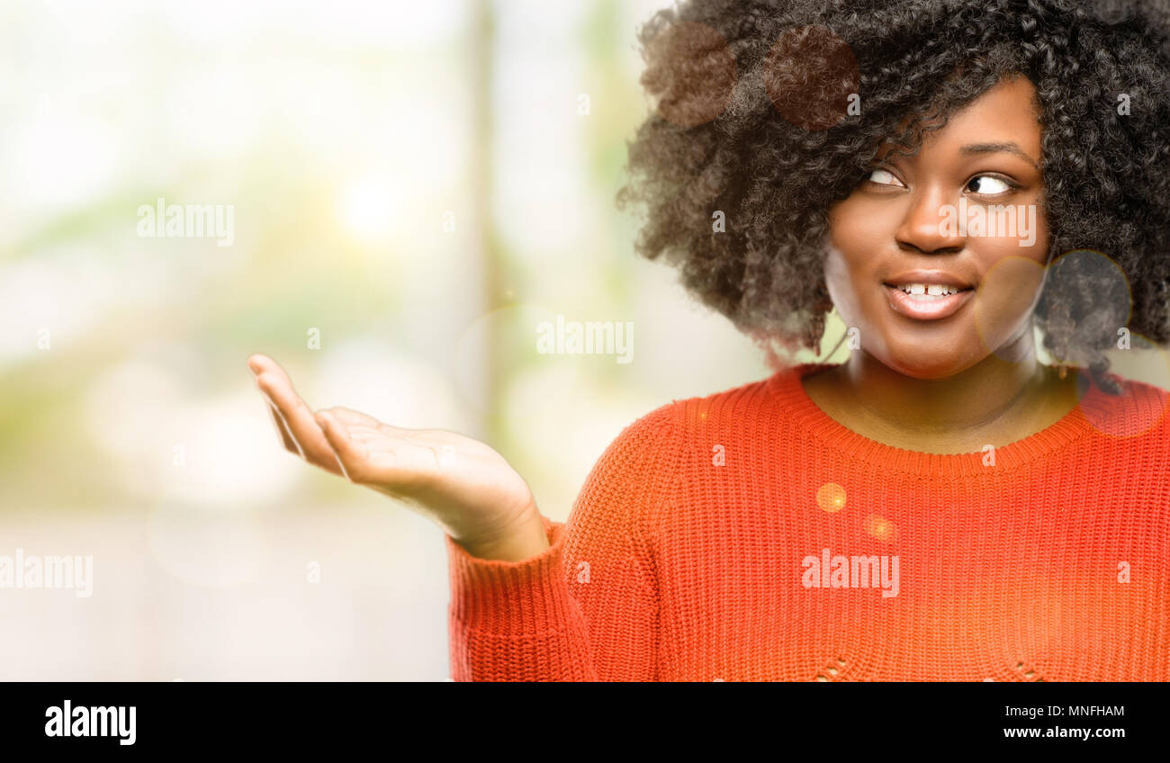 Beautiful african woman holding something in his empty hand, outdoor ...