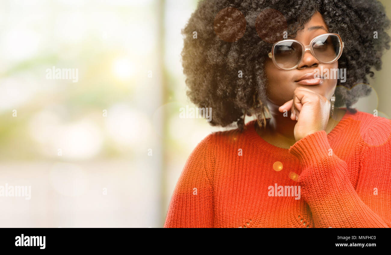 Beautiful african woman thinking and looking up expressing doubt and ...