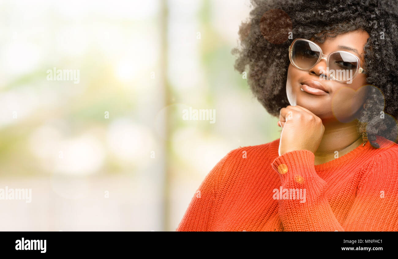 Beautiful african woman thinking and looking up expressing doubt and ...