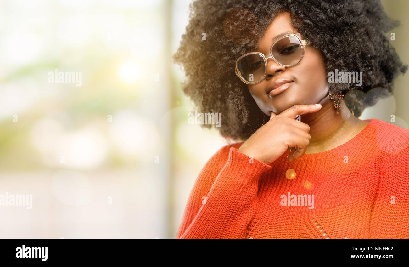 Beautiful african woman thinking and looking up expressing doubt and ...