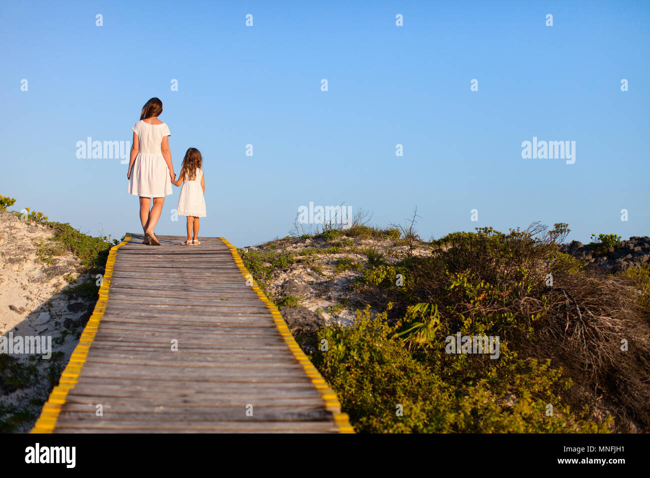 Back view of mother and daughter walking along a wooden path Stock ...