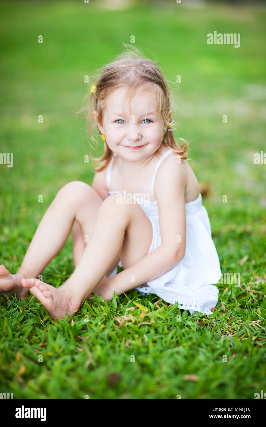 Adorable little girl sitting on a grass Stock Photo - Alamy
