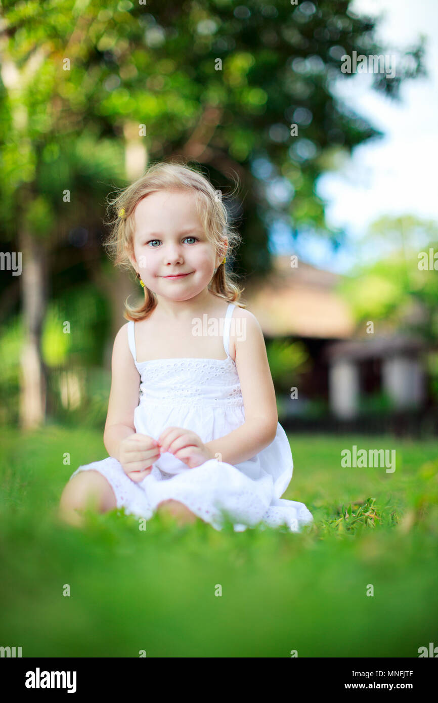 Portrait of adorable little girl sitting on grass Stock Photo - Alamy