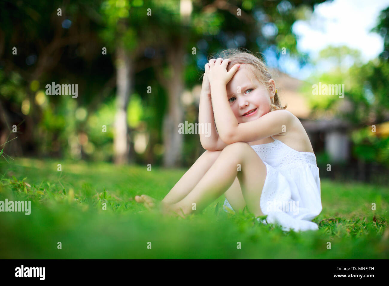 Adorable little girl sitting on a grass Stock Photo - Alamy