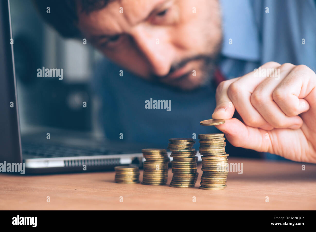 Finances and budgeting, careful businessman stacking coins on office ...