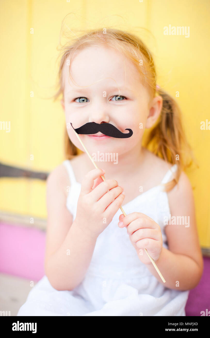 Adorable little girl holding mustache party accessory Stock Photo - Alamy