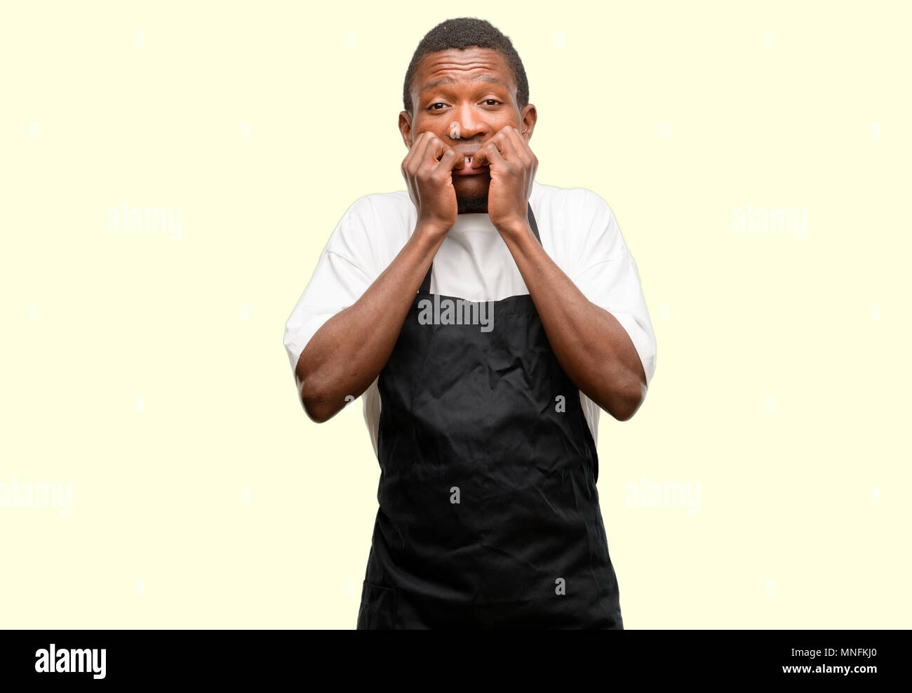 African man shop owner wearing apron terrified and nervous expressing ...