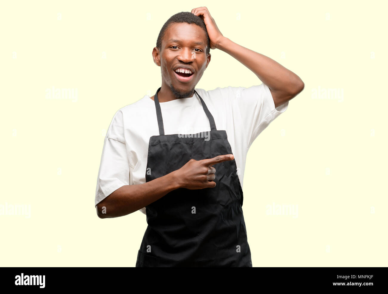 African man shop owner wearing apron pointing away side with finger ...