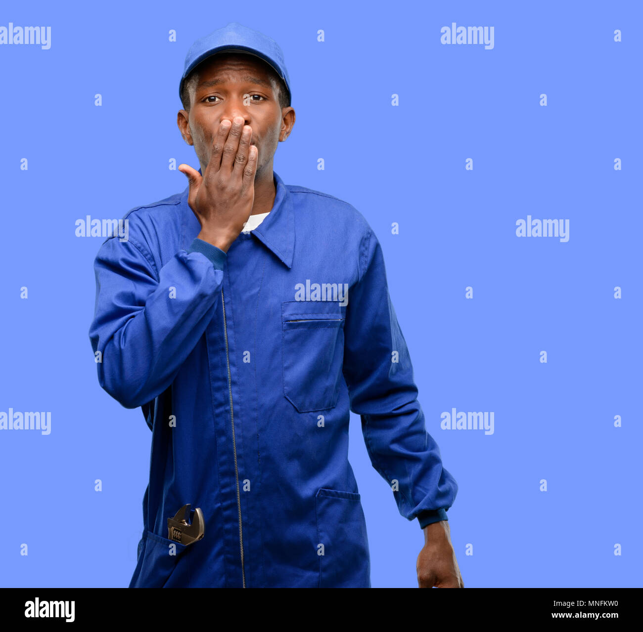 African black plumber man covers mouth in shock, looks shy, expressing ...