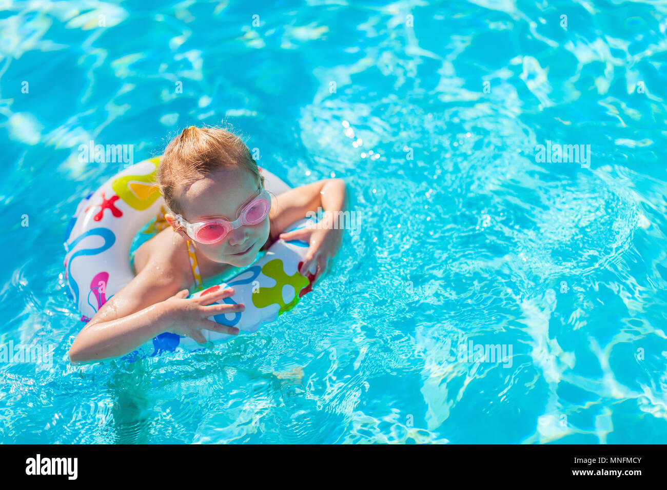 Adorable little girl at swimming pool having fun during summer vacation ...