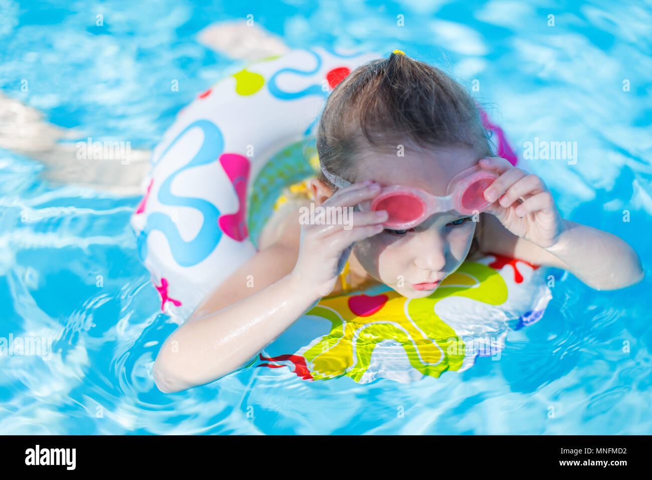 Adorable little girl at swimming pool having fun during summer vacation ...