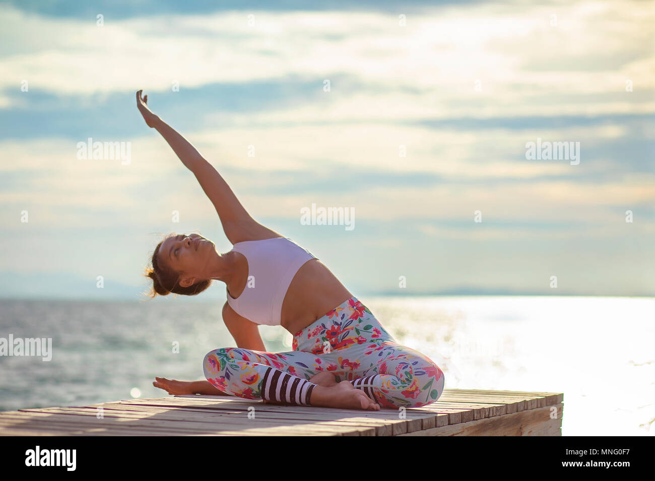 younger woman playing yoga pose on sea pier Stock Photo - Alamy