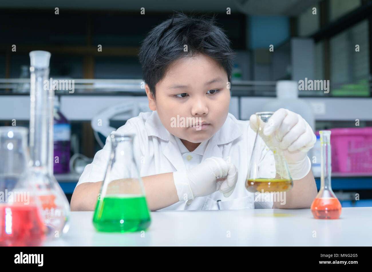 kid scientist in lab coat making experiment with test tube in chemical ...