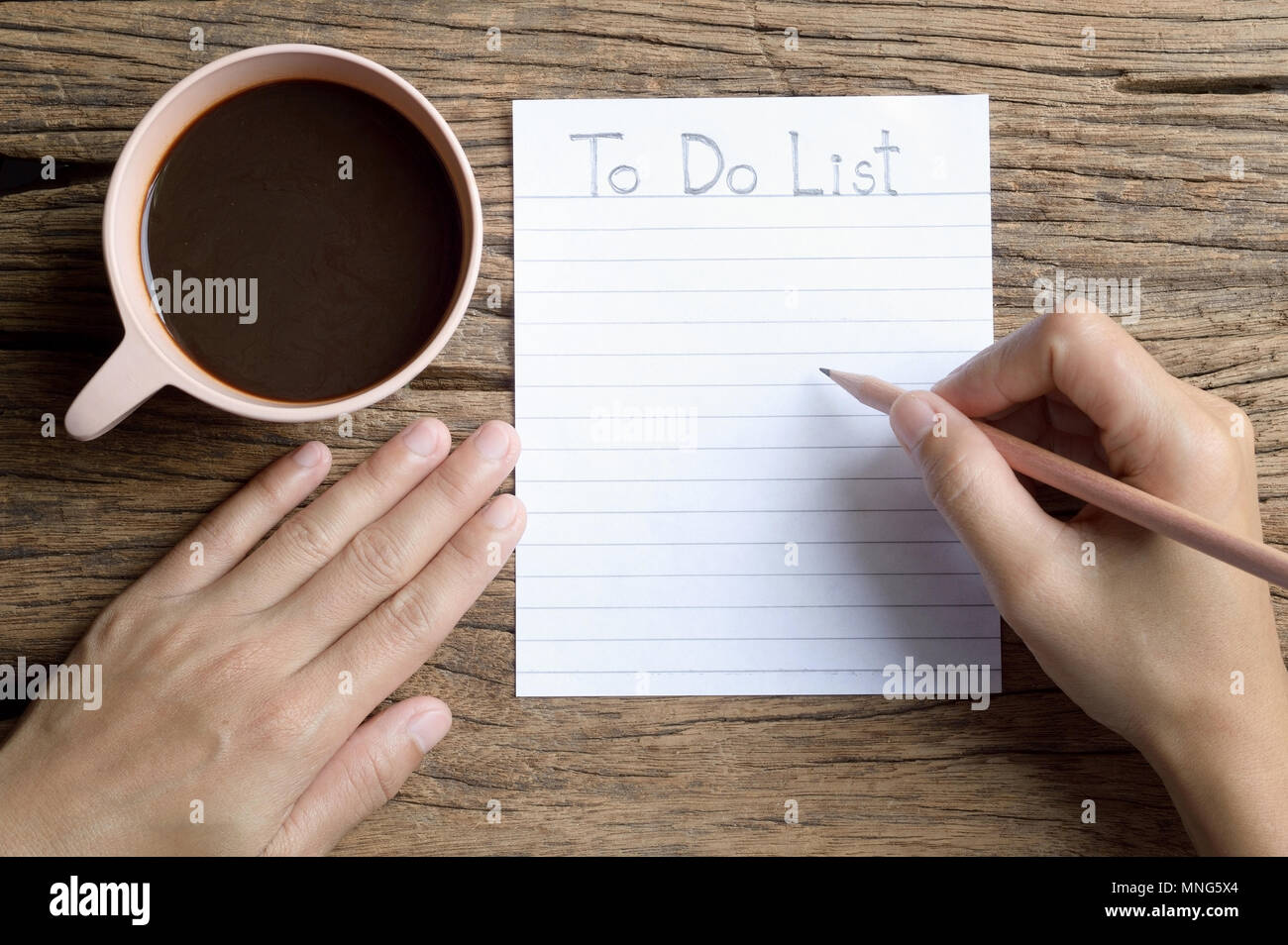 close up of woman hand writing to do list in blank paper on wooden ...