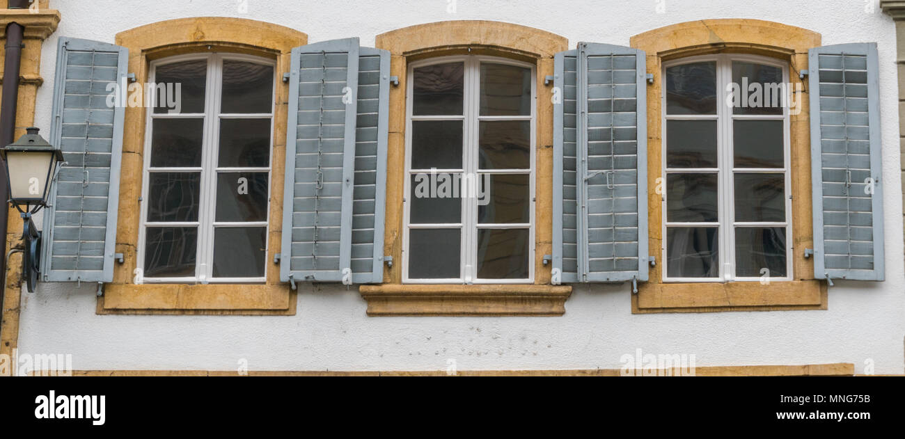 close up view of three windows with wooden window shutters in blue ...