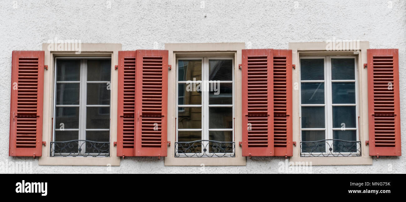 close up view of three windows with wooden window shutters in red Stock ...