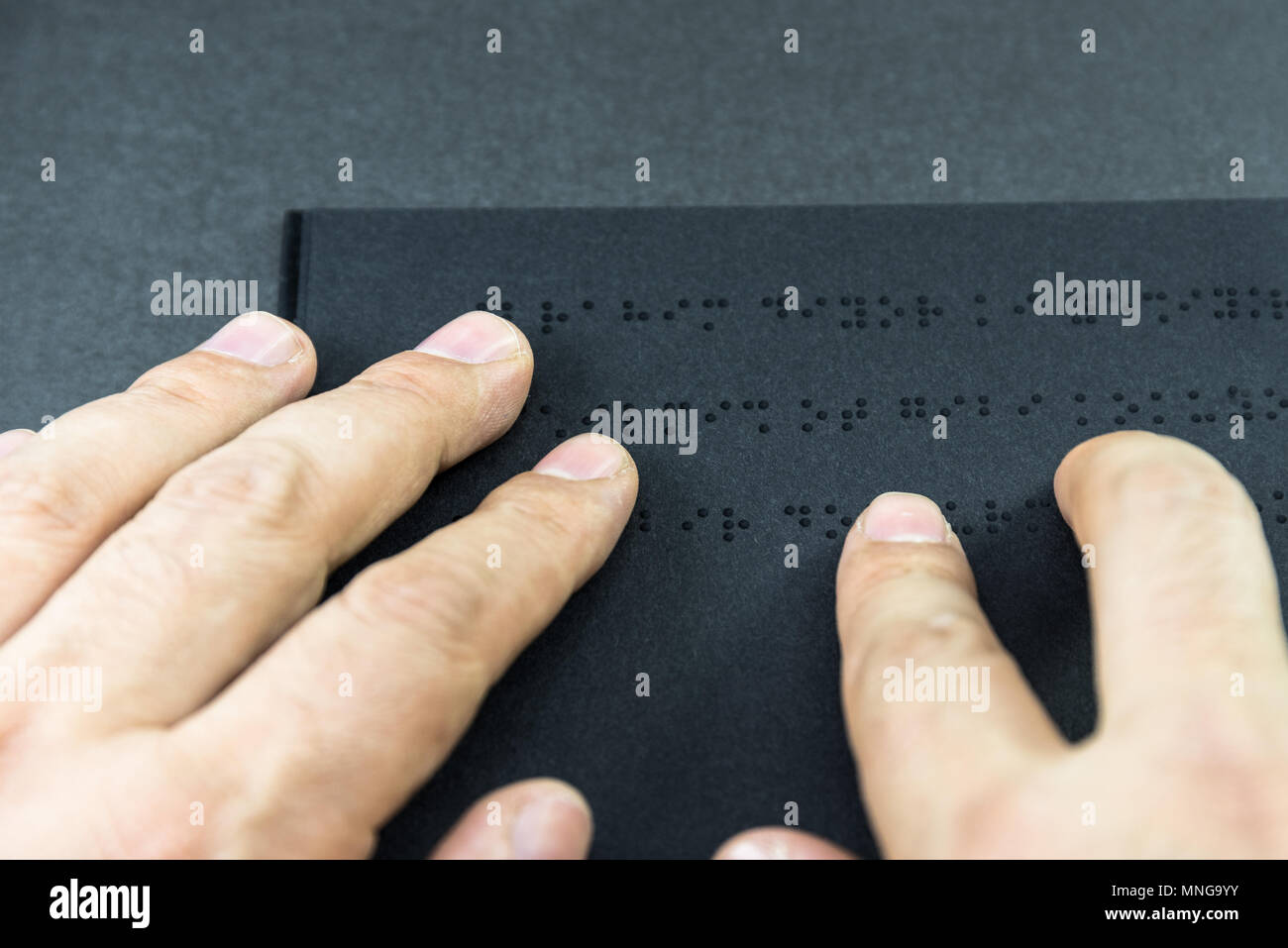 Top view of hand of a blind person reading a book written in braille ...