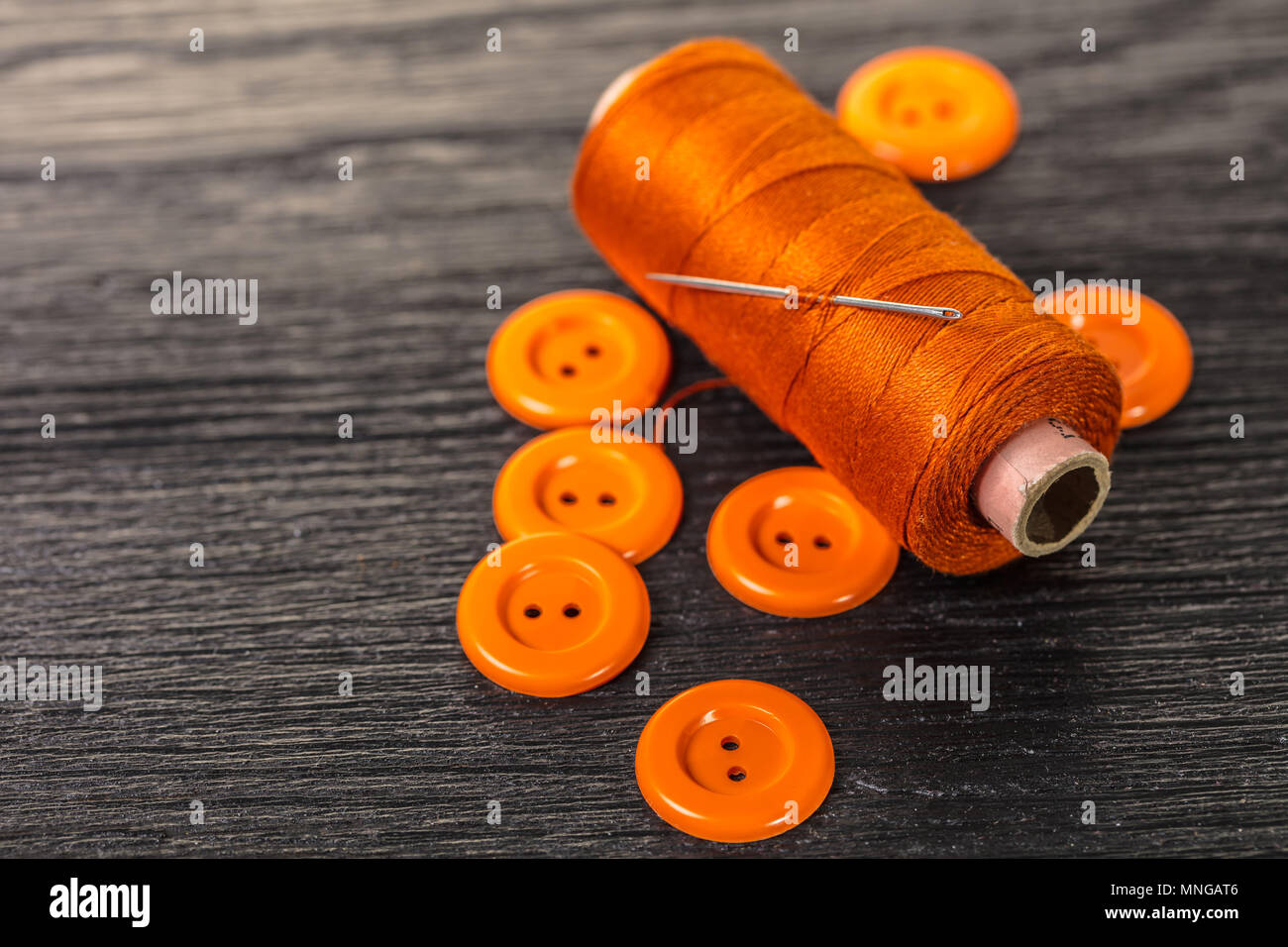 spool of threads and buttons on a wooden background Stock Photo - Alamy