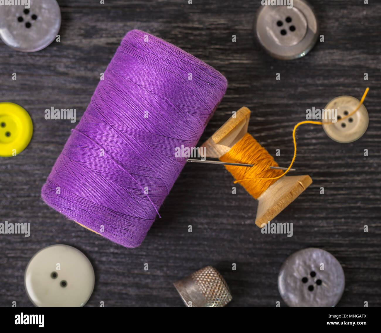 spool of threads and buttons on a wooden background Stock Photo - Alamy