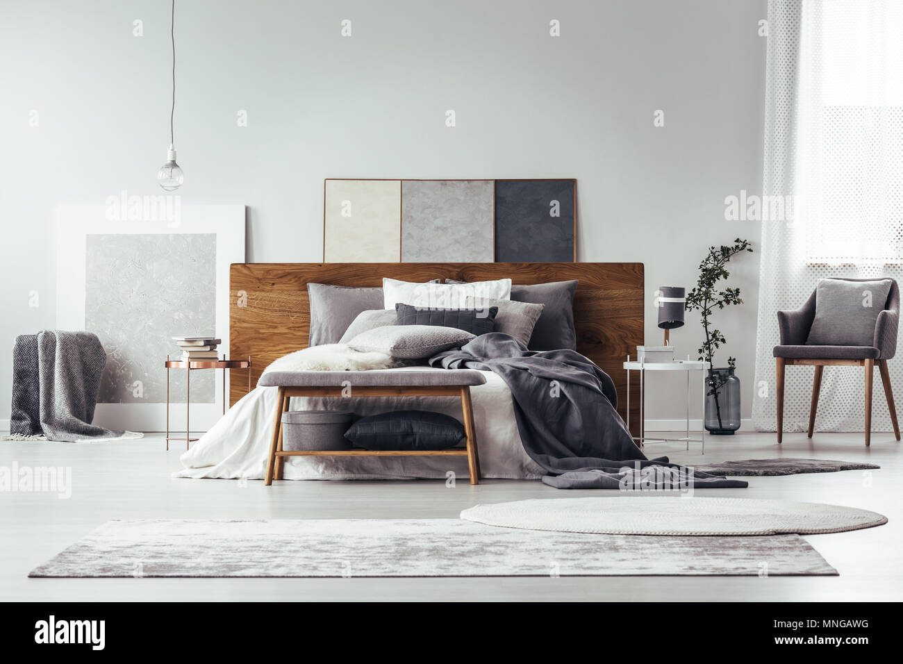 Simple painting on wooden bedhead of bed with pillows in grey bedroom ...