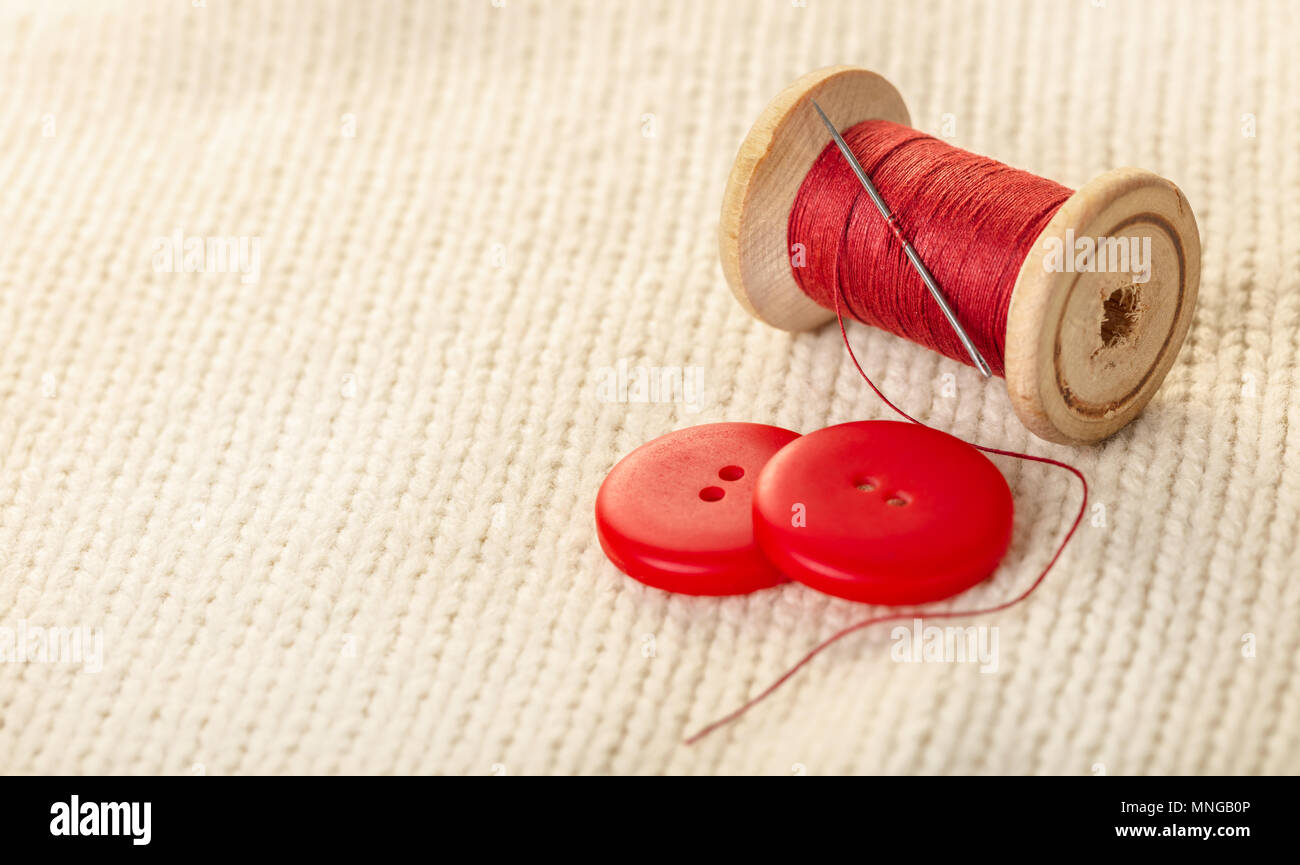 colored thread and buttons on white knitted fabric Stock Photo - Alamy