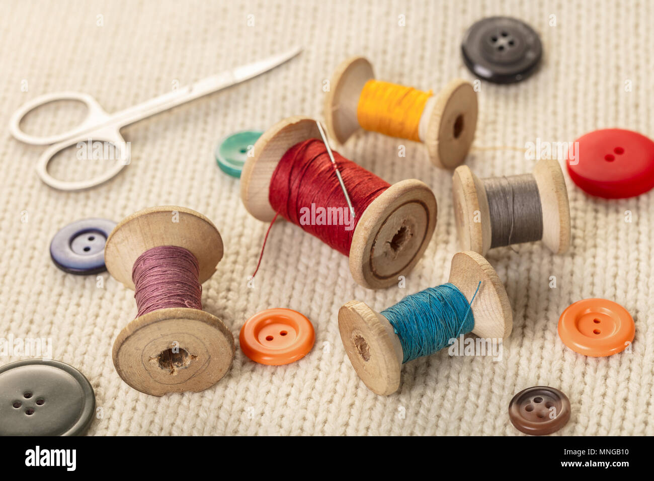 colorful threads and buttons on white knitted fabric Stock Photo - Alamy