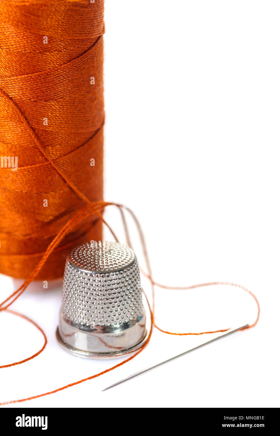 needle with an orange thread and a thimble on white background Stock ...