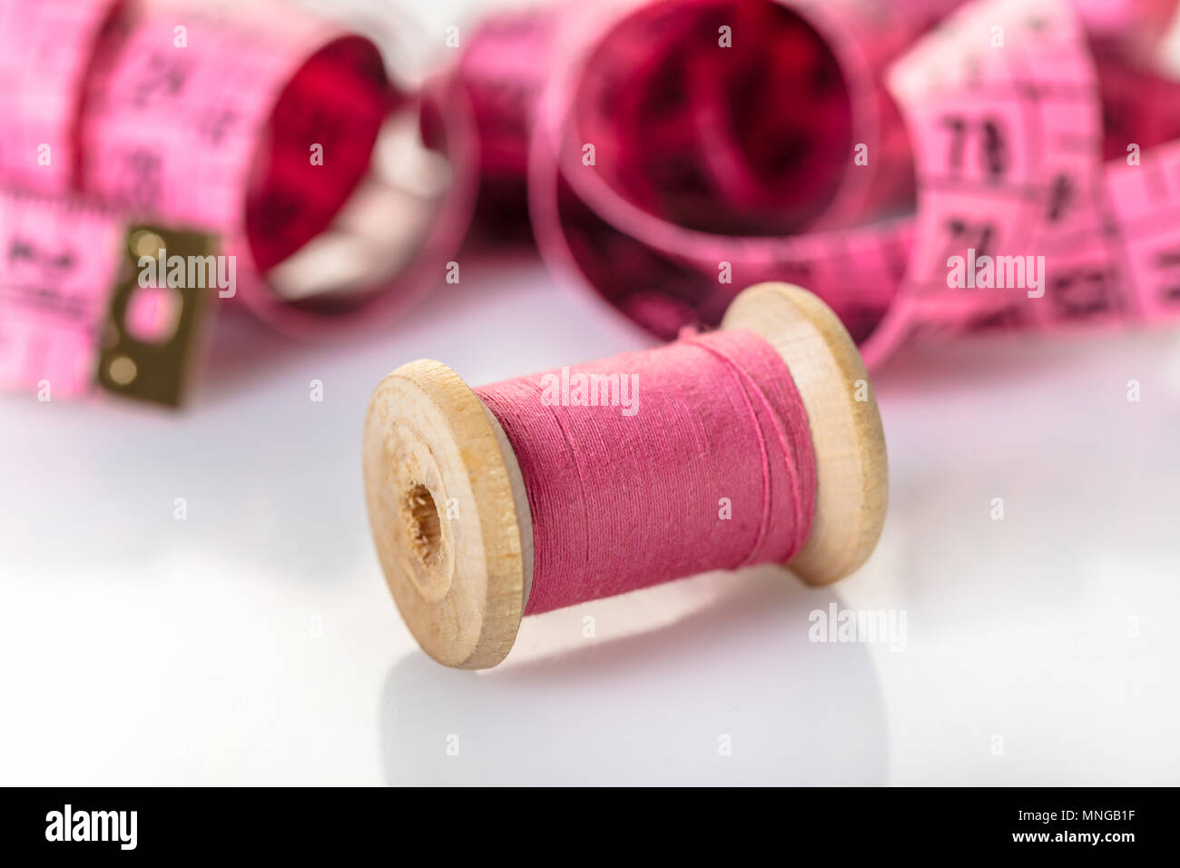 spool of pink thread and meter on white background Stock Photo - Alamy