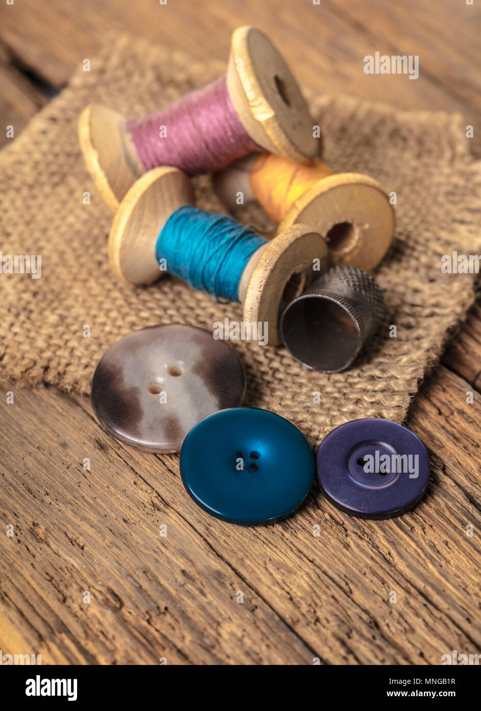 spool of threads and buttons on a wooden background Stock Photo - Alamy