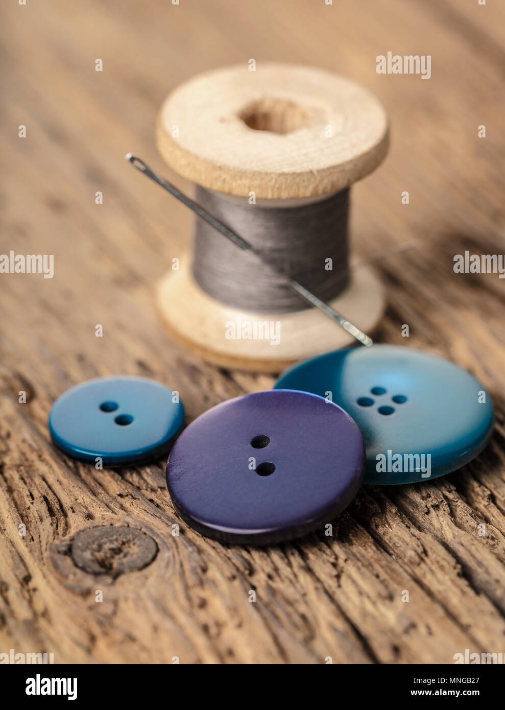 spool of threads and buttons on a wooden background Stock Photo - Alamy