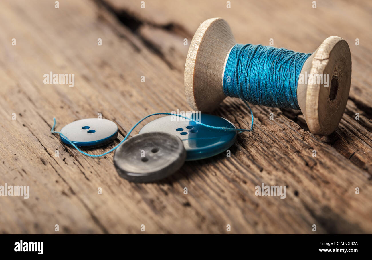 spool of threads and buttons on a wooden background Stock Photo - Alamy