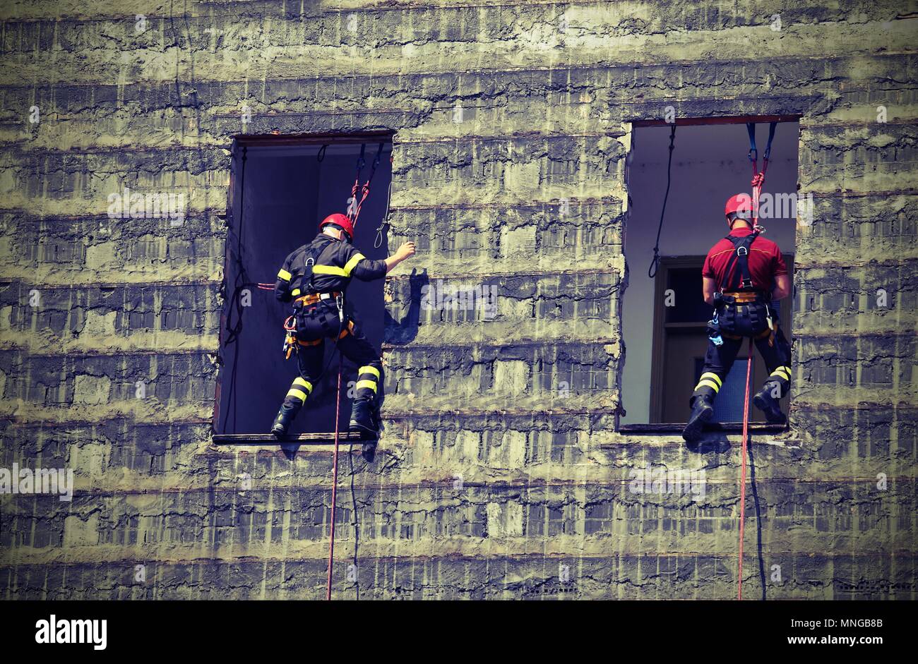 two climbers of firefighters climbing a wall of barracks fire ...