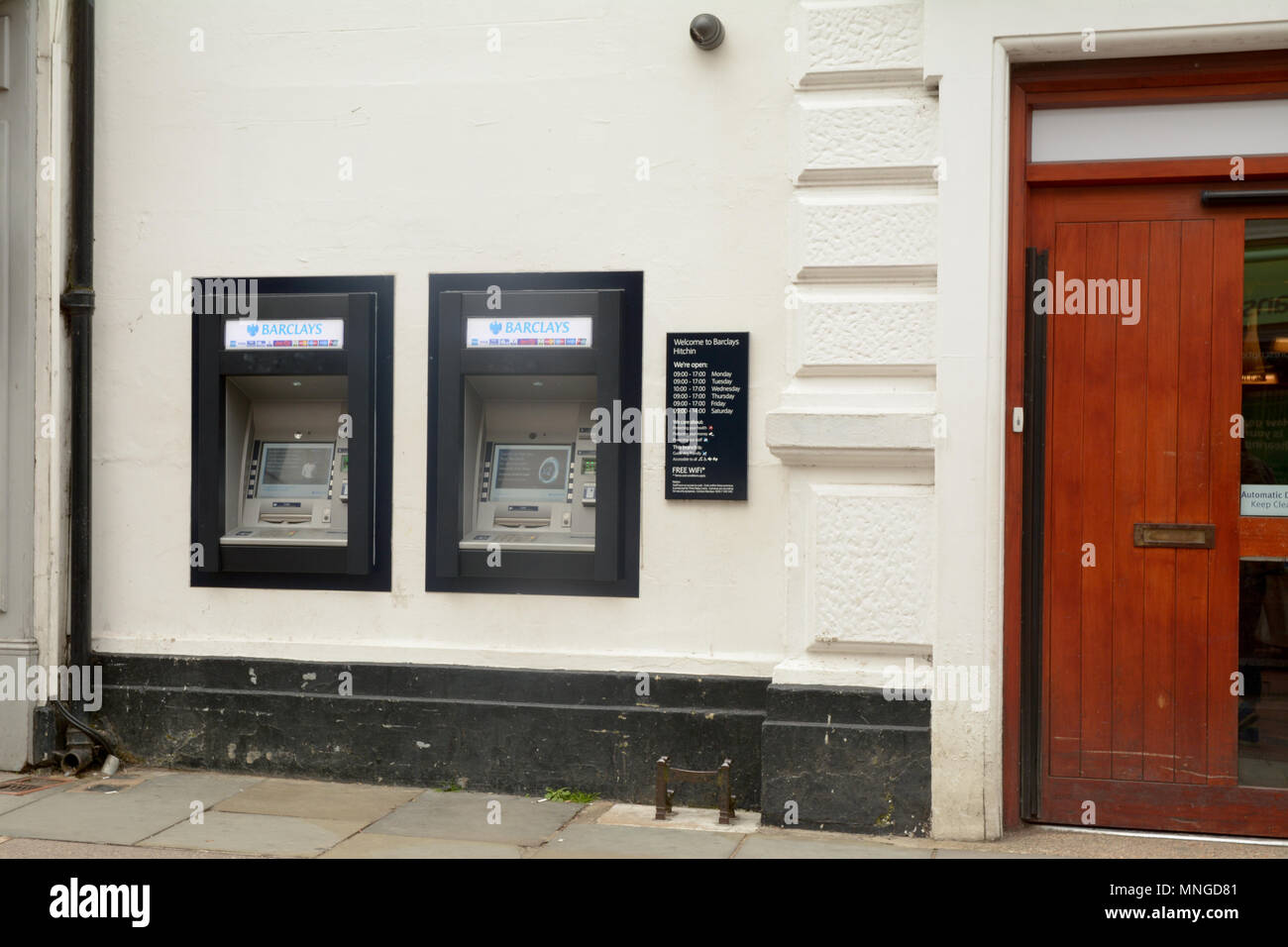 Two ATM cash machines outside branch of Barclays Bank with security ...