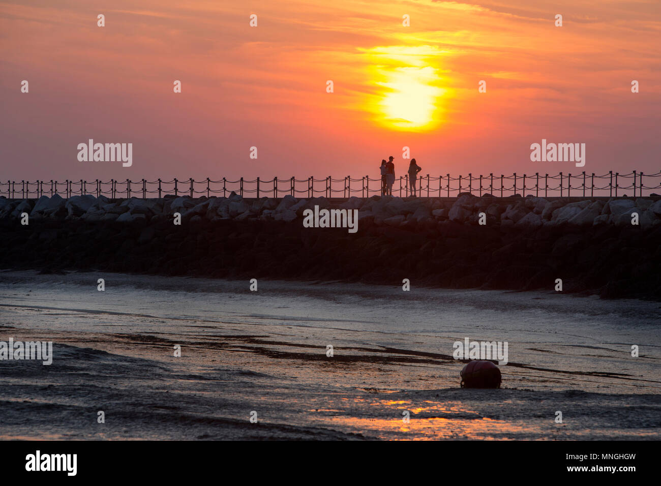 People talking on a harbour wall at sunset Stock Photo - Alamy