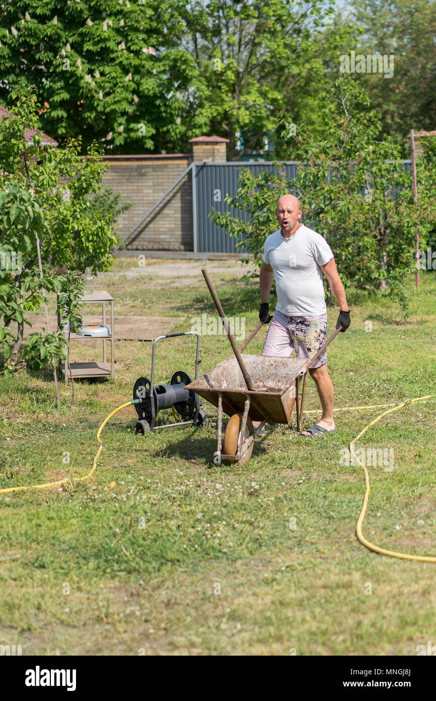 man pushing wheelbarrow. Young man pushing a wheelbarrow on the farm ...