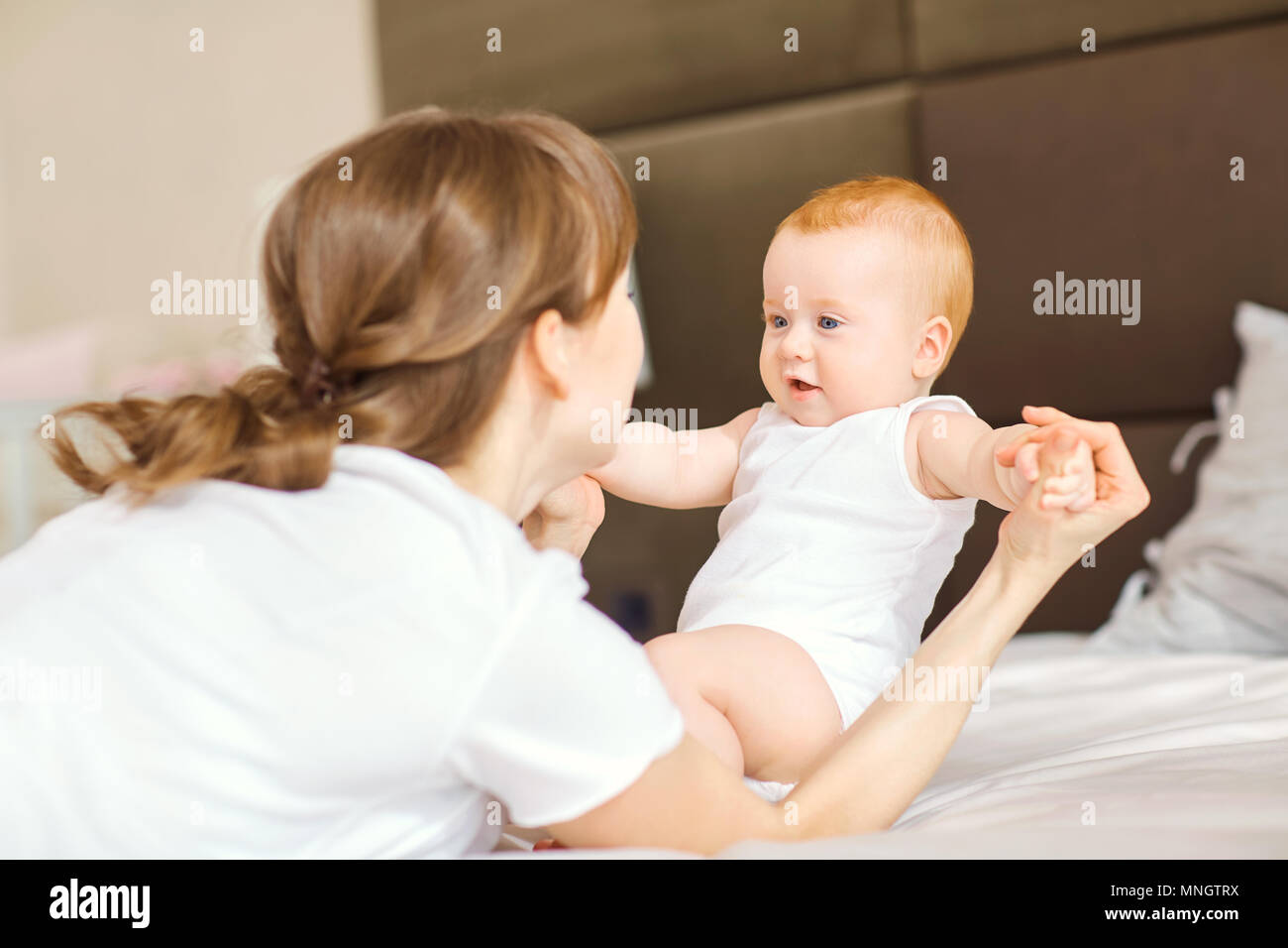 Happy mother hugging baby lying on the bed indoors Stock Photo - Alamy