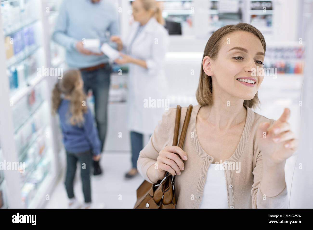 Reflective pleasant woman distracting in drugstore Stock Photo - Alamy