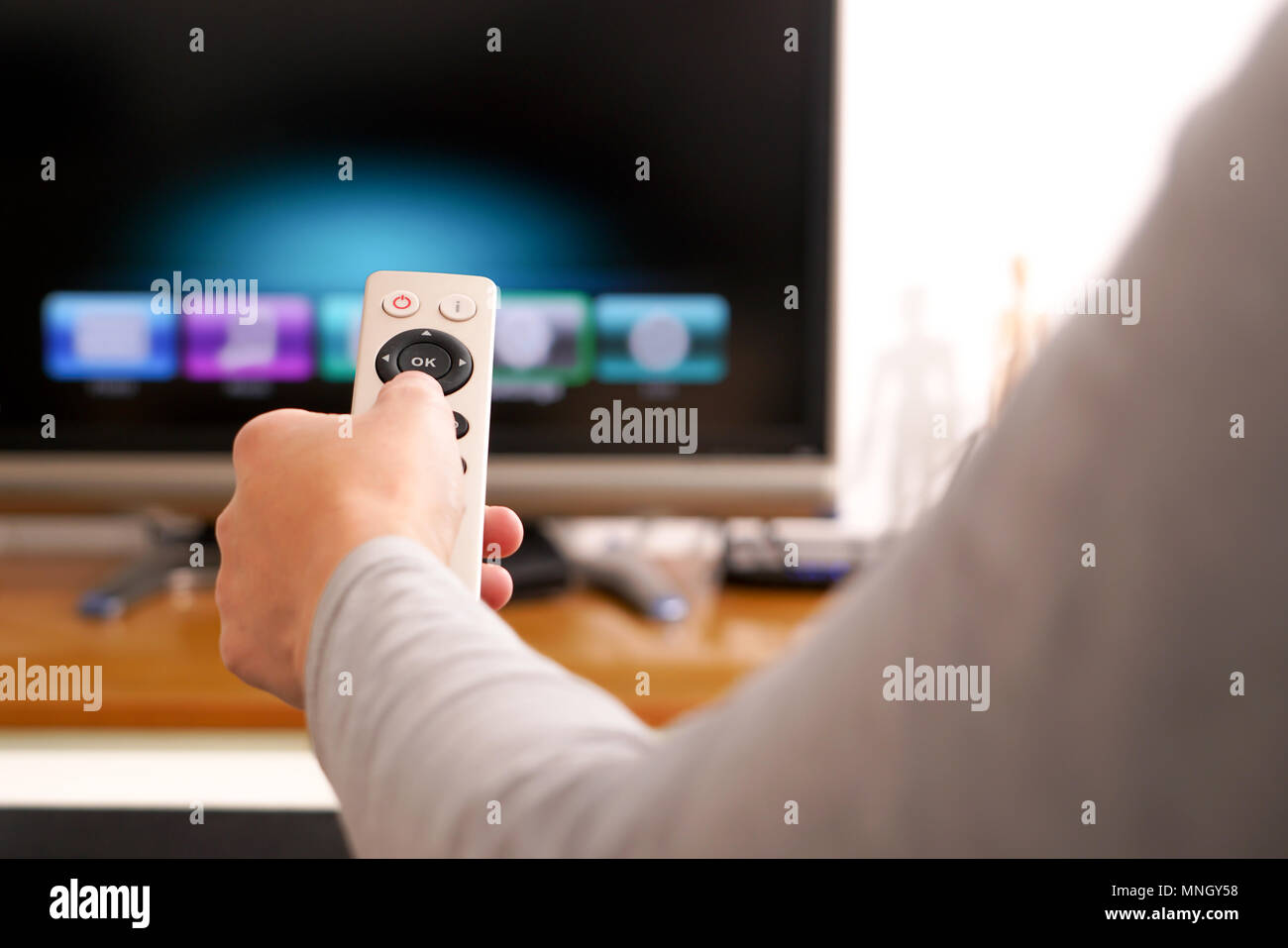 a women hand hold the remote control of the TV box in the living room ...